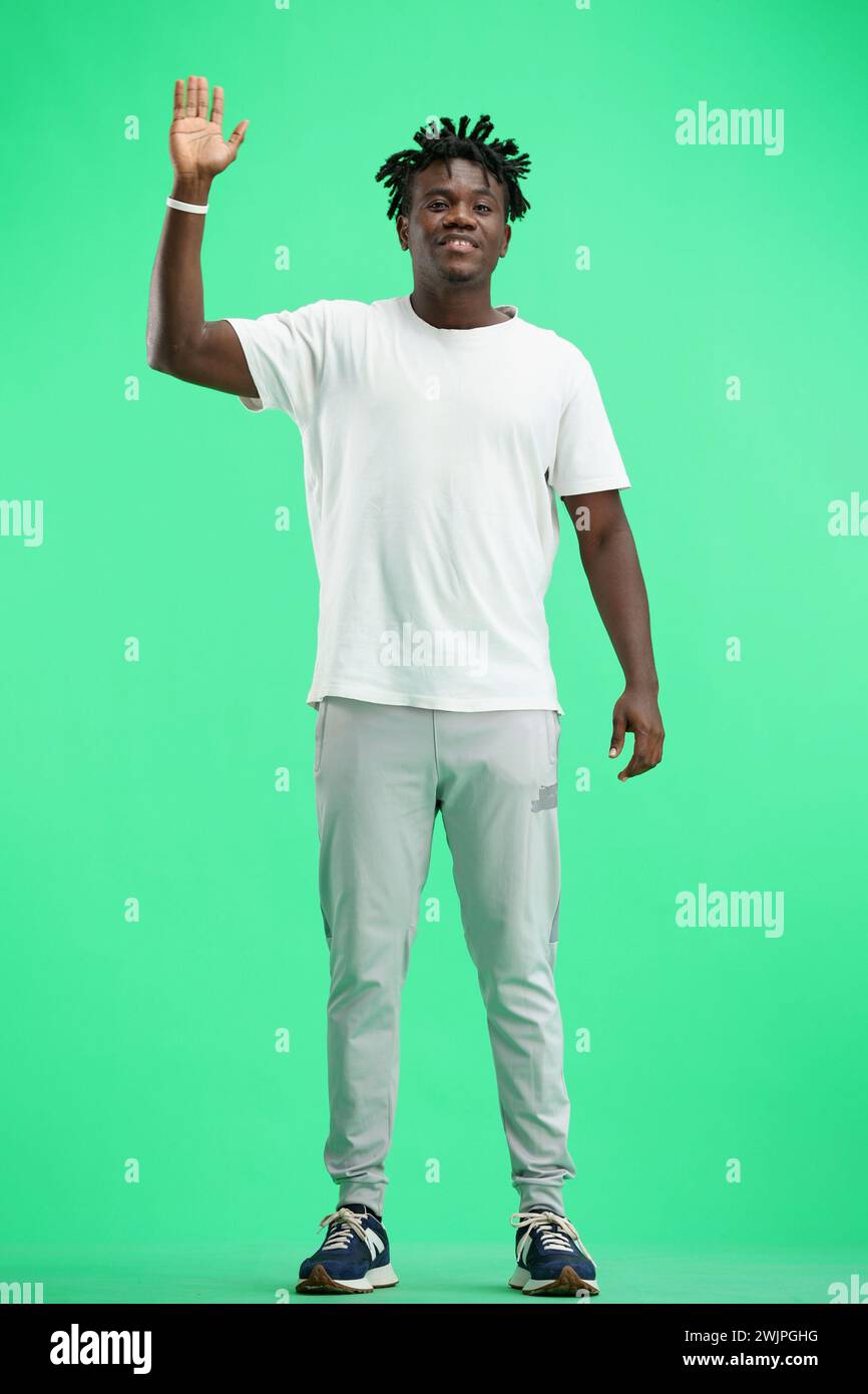A man, full-length, on a green background, waving his hand Stock Photo ...