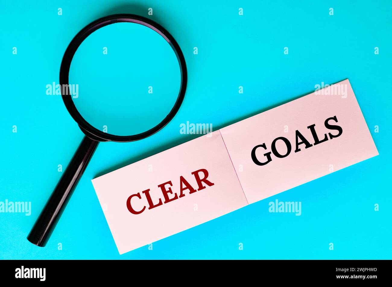 Top view of magnifying glass and notepad with Clear Goals text on light ...
