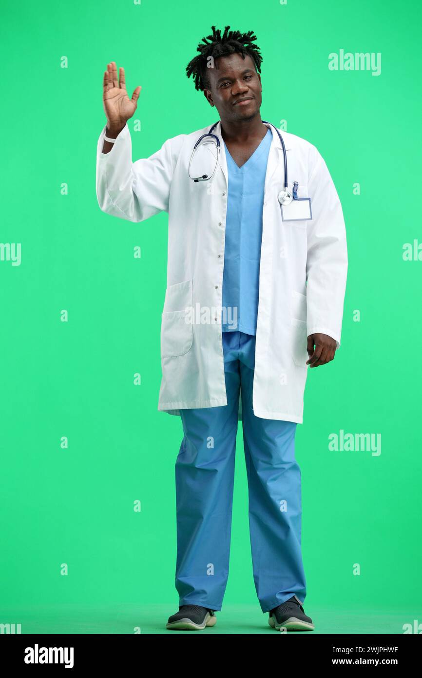The doctor, in full height, on a green background, waving his hand ...