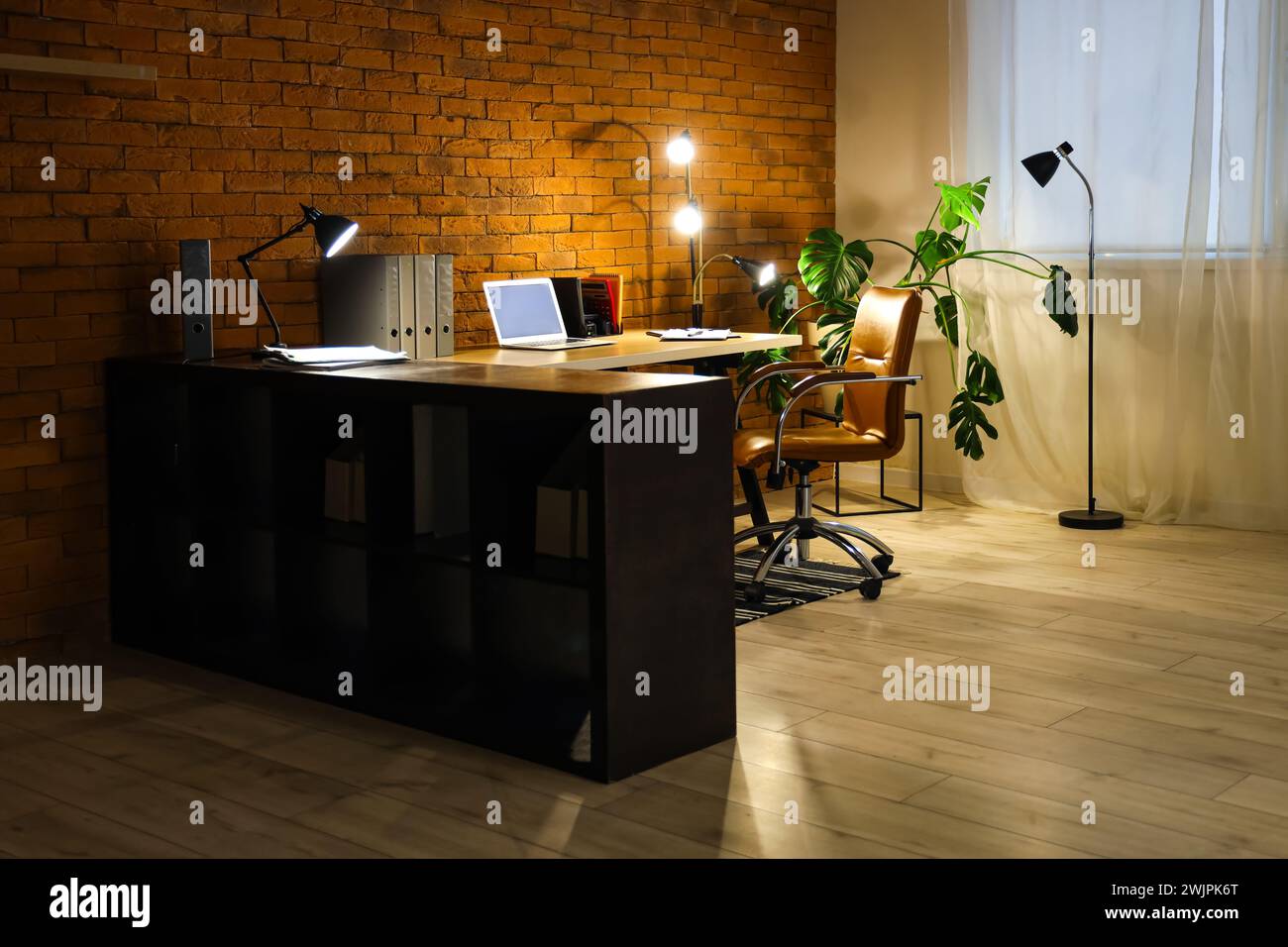 Interior of dark office with workplace, blank laptop and glowing lamps ...