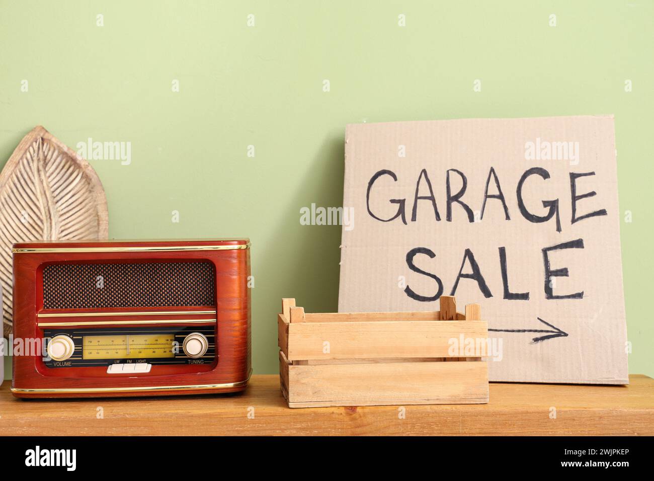 Vintage radio, basket and cardboard with text GARAGE SALE near green ...