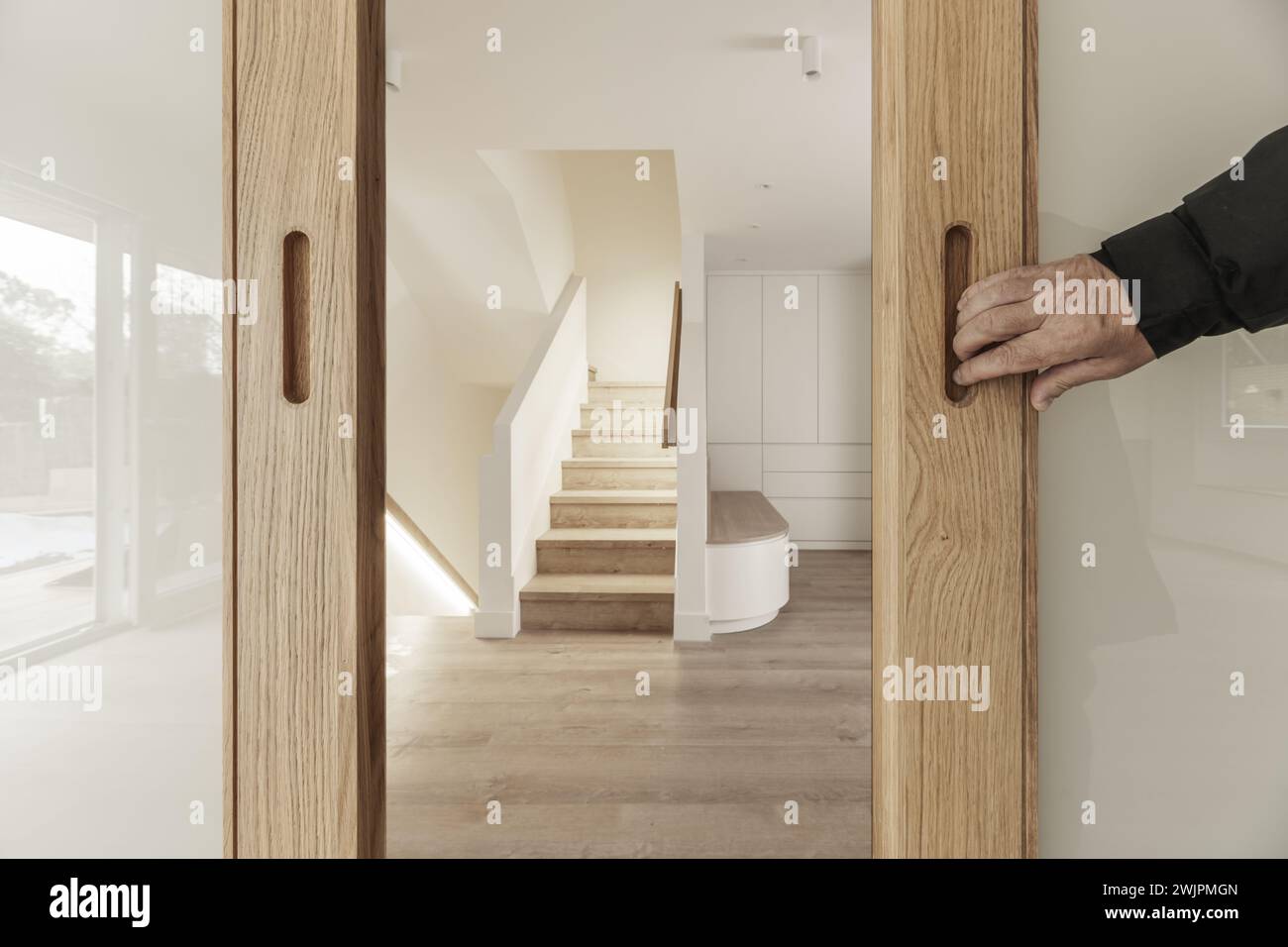Some oak wood and translucent glass doors opened by the hand of a man ...