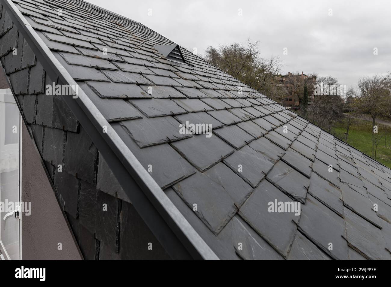 Sloped roofs of a house with black slate tiles Stock Photo - Alamy