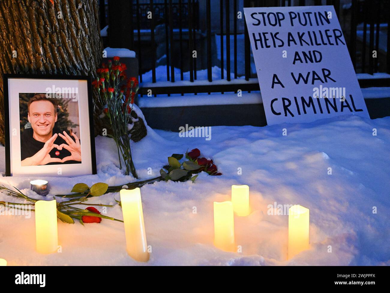 Flowers and candles are shown next to a photograph at a makeshift ...
