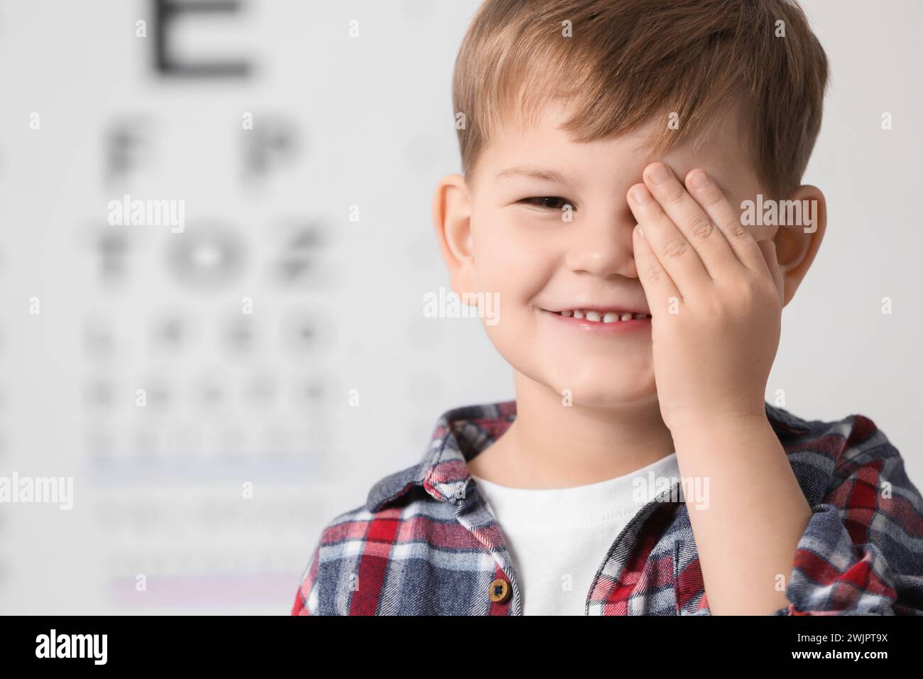 Little boy covering her eye against vision test chart Stock Photo - Alamy