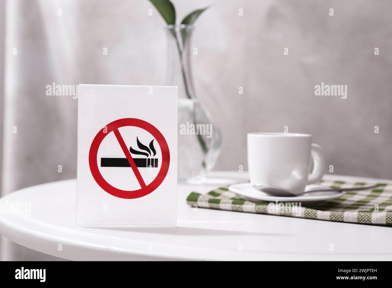 No Smoking sign and cup of coffee on white table indoors Stock Photo ...