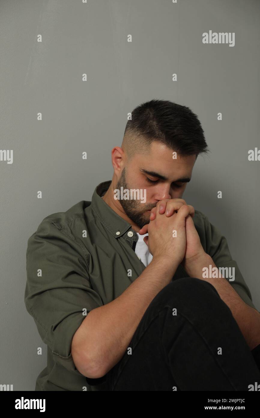 Portrait of sad man near light grey wall Stock Photo - Alamy