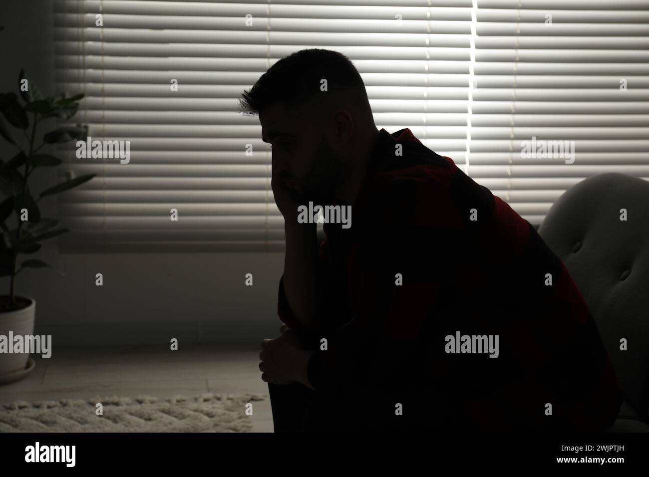 Silhouette of sad man near closed blinds indoors. Space for text Stock ...