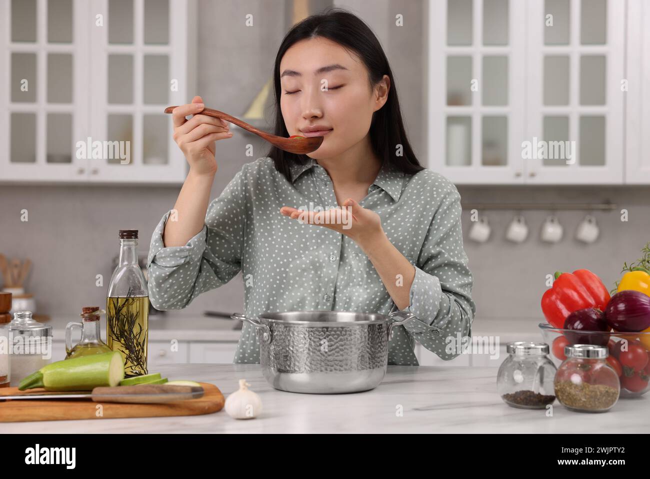 Beautiful woman tasting food after cooking in kitchen Stock Photo - Alamy