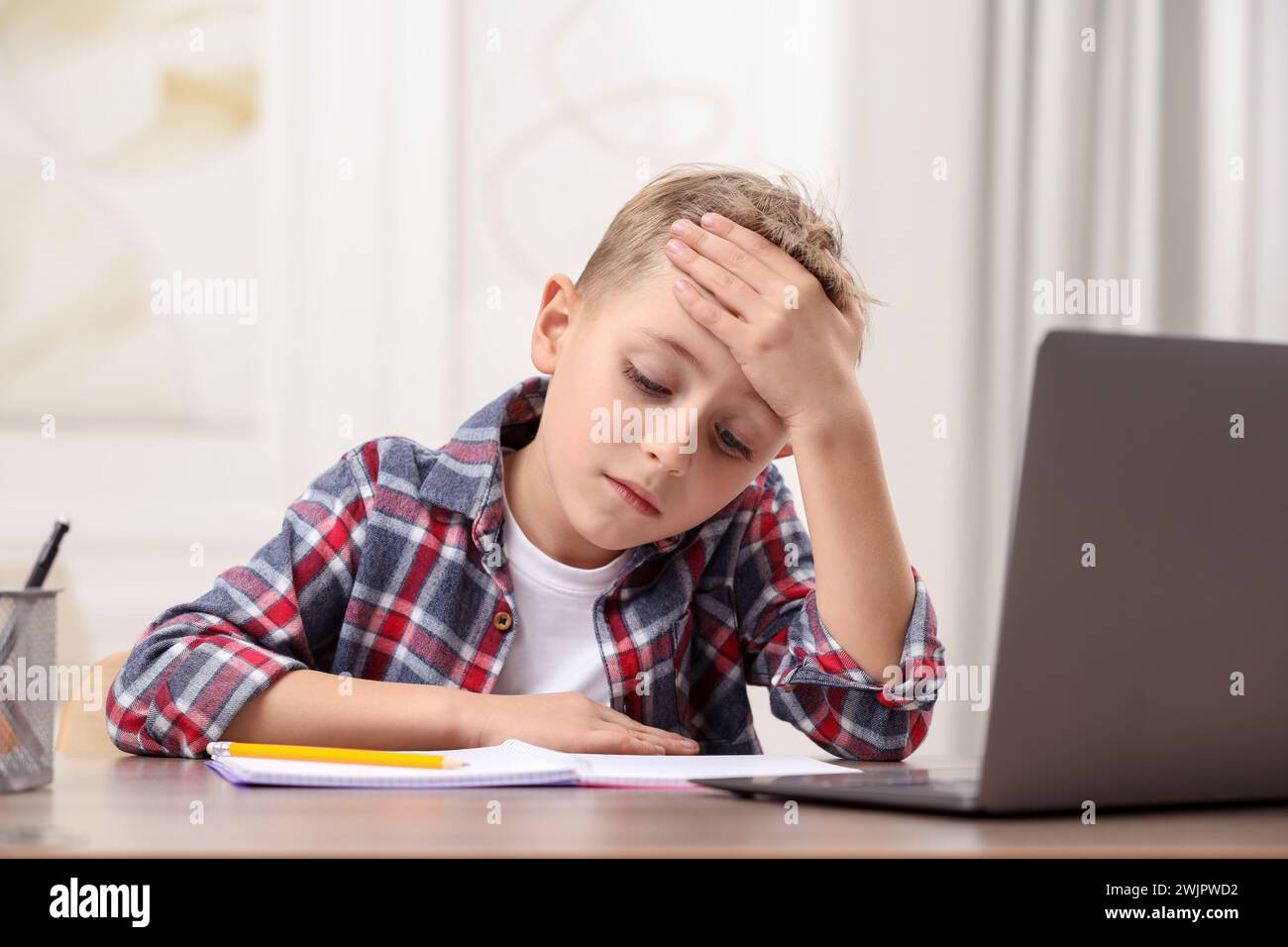 Little boy suffering from headache at wooden desk indoors Stock Photo ...