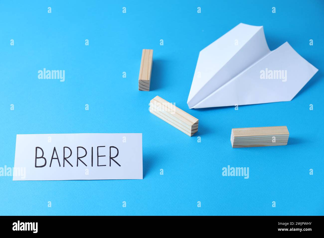 Paper plane movement blocked by wooden blocks and card with word ...