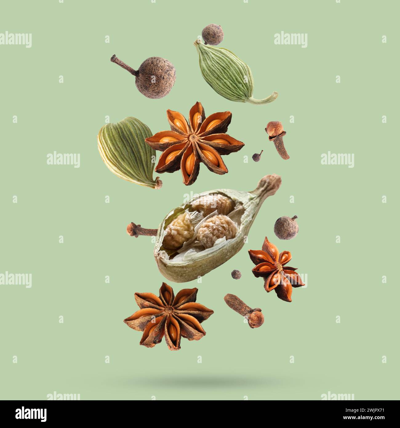 Different spices falling on light green background Stock Photo - Alamy