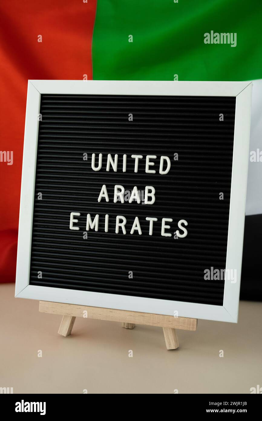 Text UNITED ARAB EMIRATES on background waving flag of UAE. National ...