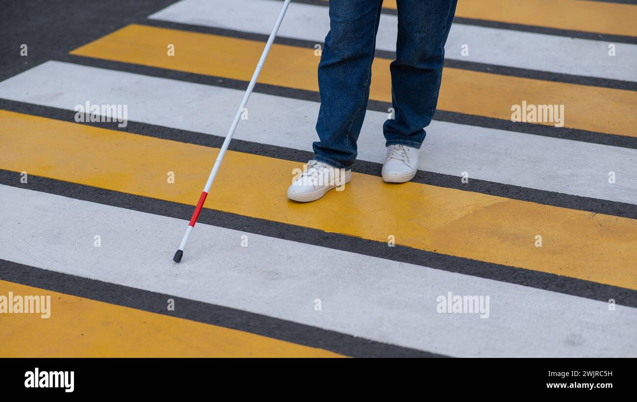 Close-up of the legs of a blind woman crossing the road at a crosswalk ...