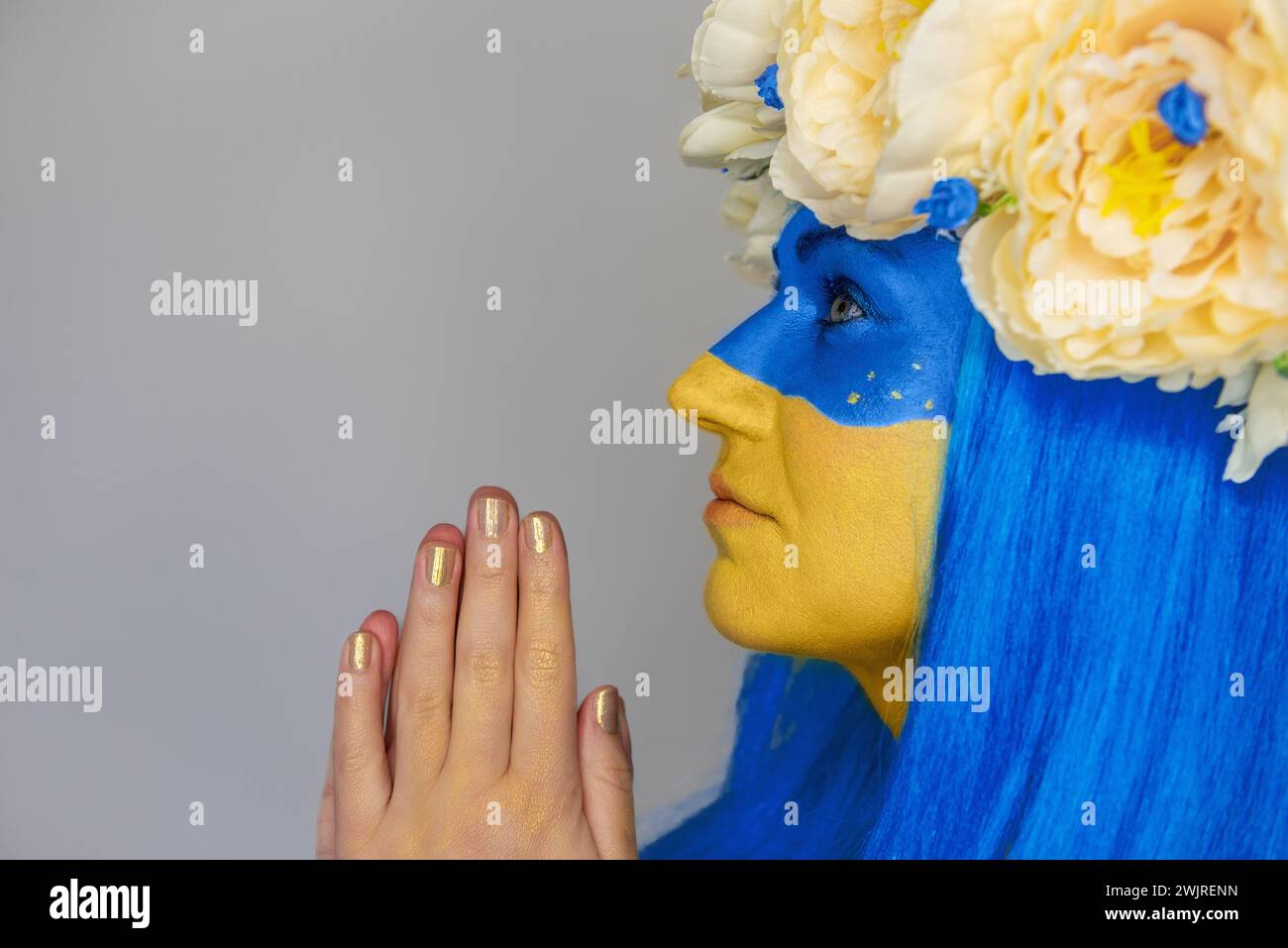 Young woman side view with yellow blue face art, wreath of peonies on ...