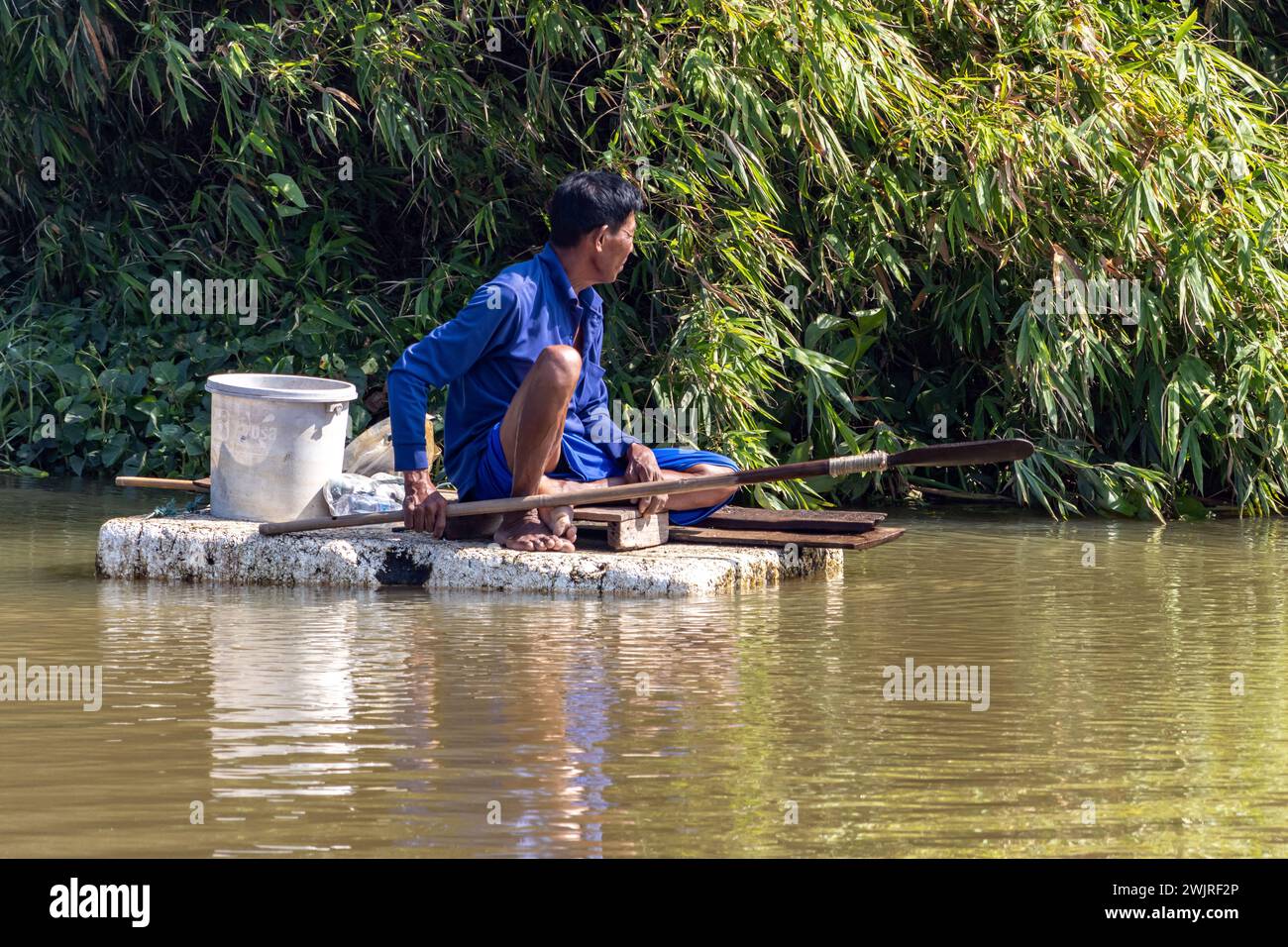 THAILAND, DEC 05 2023, Man floating on styrofoam inspects riverbank ...