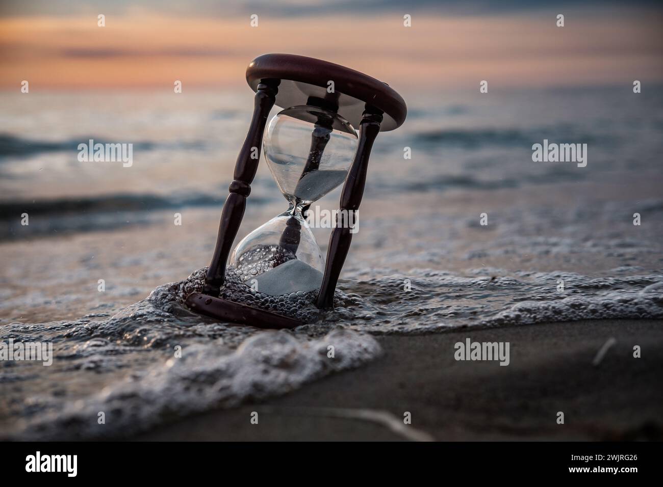 Hourglass on the shore with waves, reflecting the fleeting nature of ...