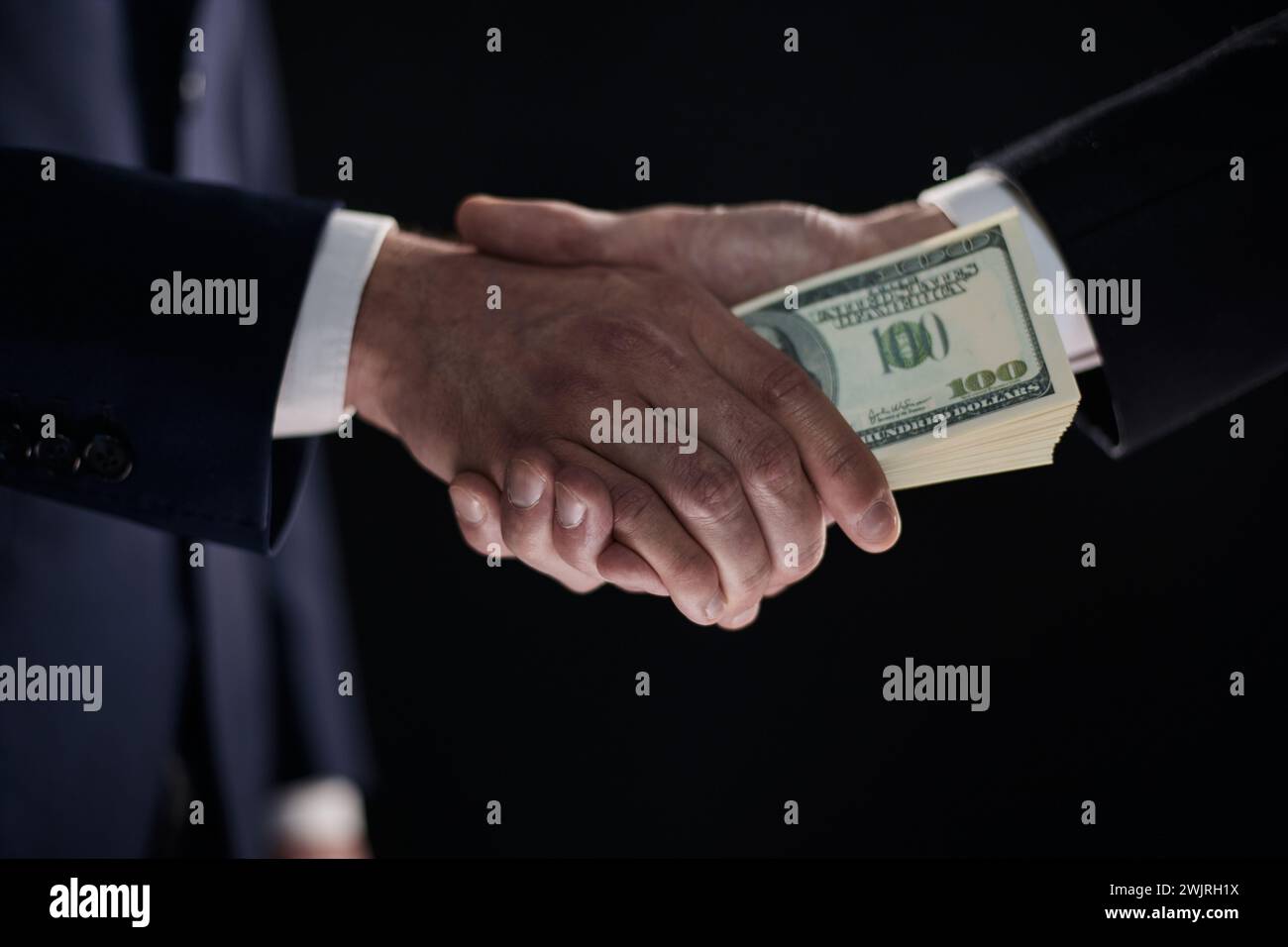 Handshake with the transfer of money on a black background Stock Photo ...