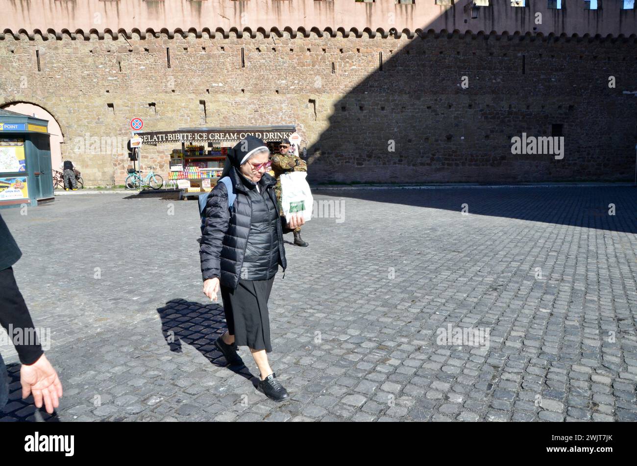 a nun crossing pebbled street with a bag of food in vatican city rome ...
