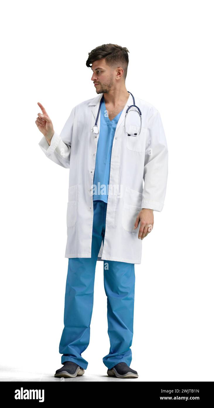 The doctor, in full height, on a white background, points to the side ...