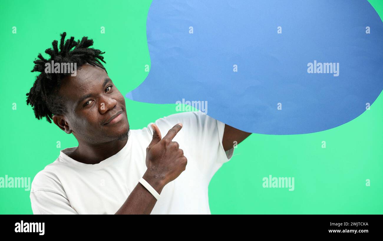 A man, close-up, on a green background, shows a blue comment sign Stock ...