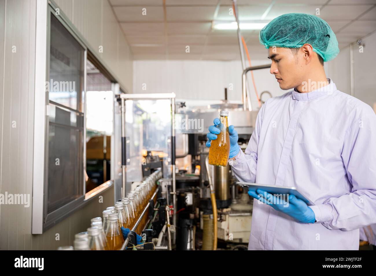 Quality control officer inspects beverage bottling factory line with ...