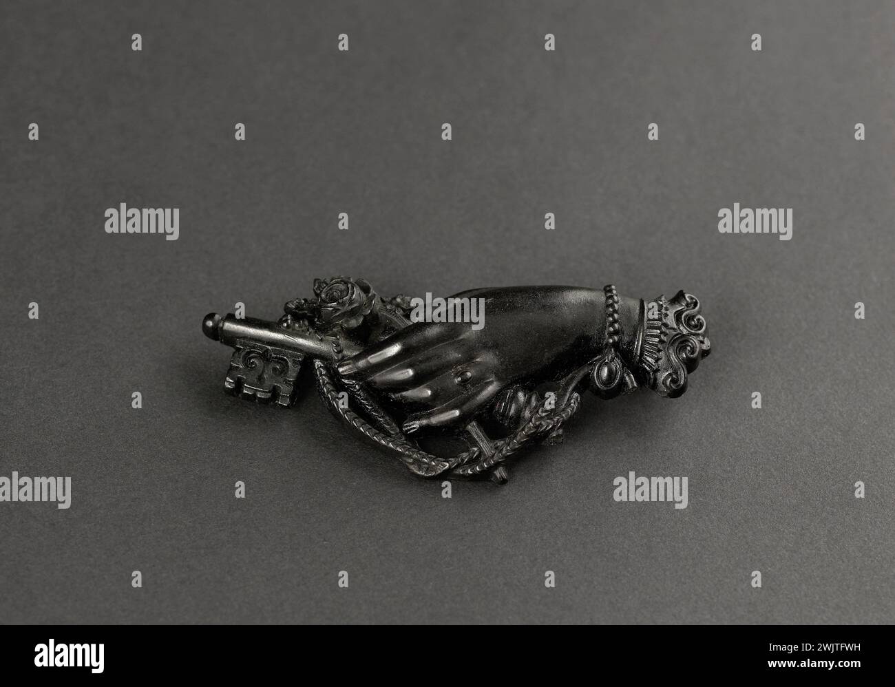 Mourning pin: Hand holding a rose and a key. Downweed, sculpted, cut ...