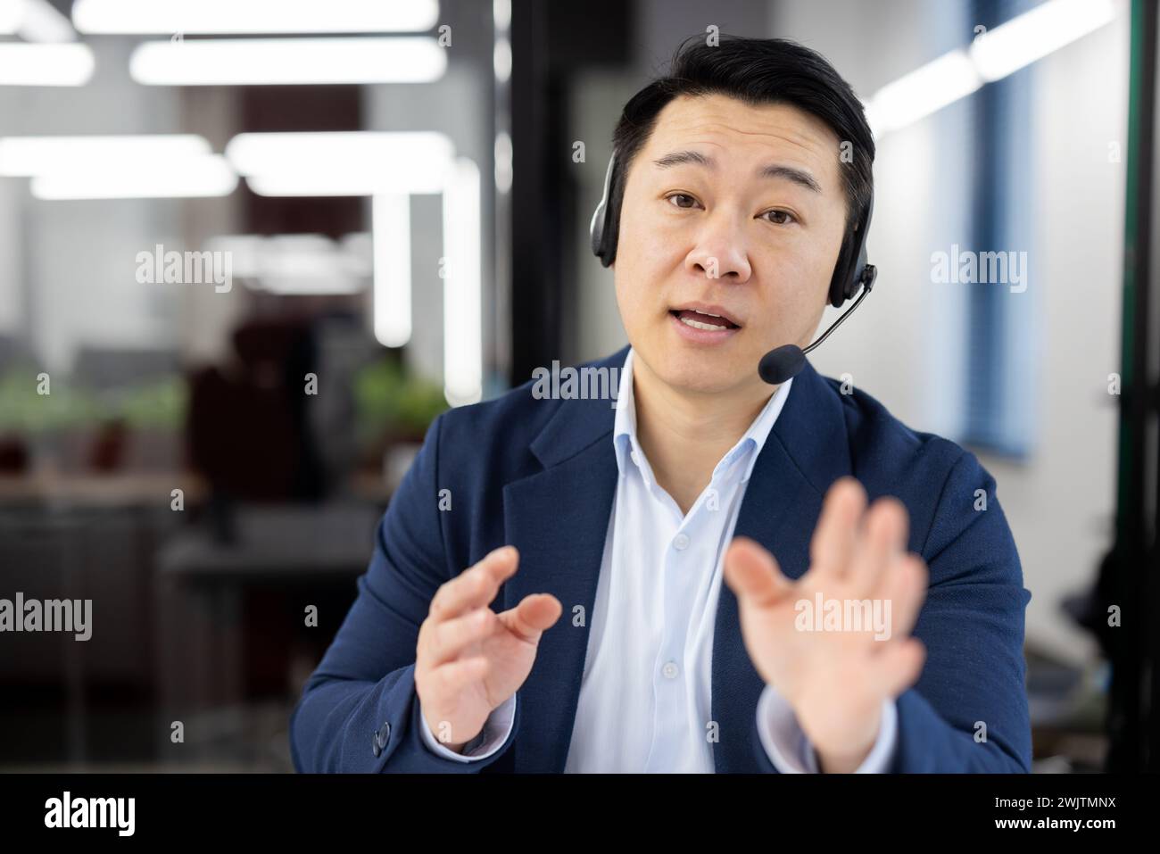 Confident Asian male support agent conversing with clients using ...