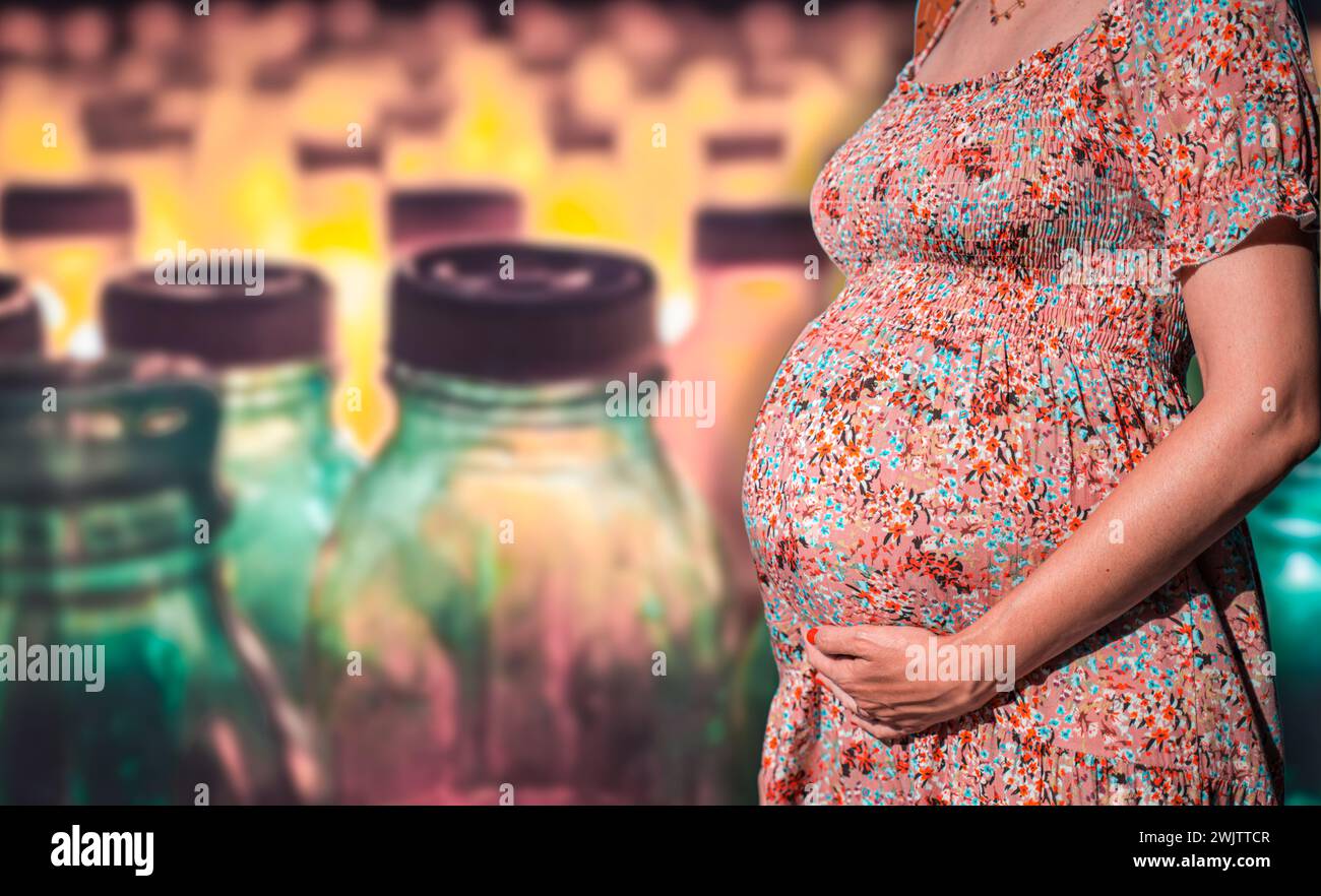 Close-up of a pregnant belly with a blurred plastic bottles on the ...