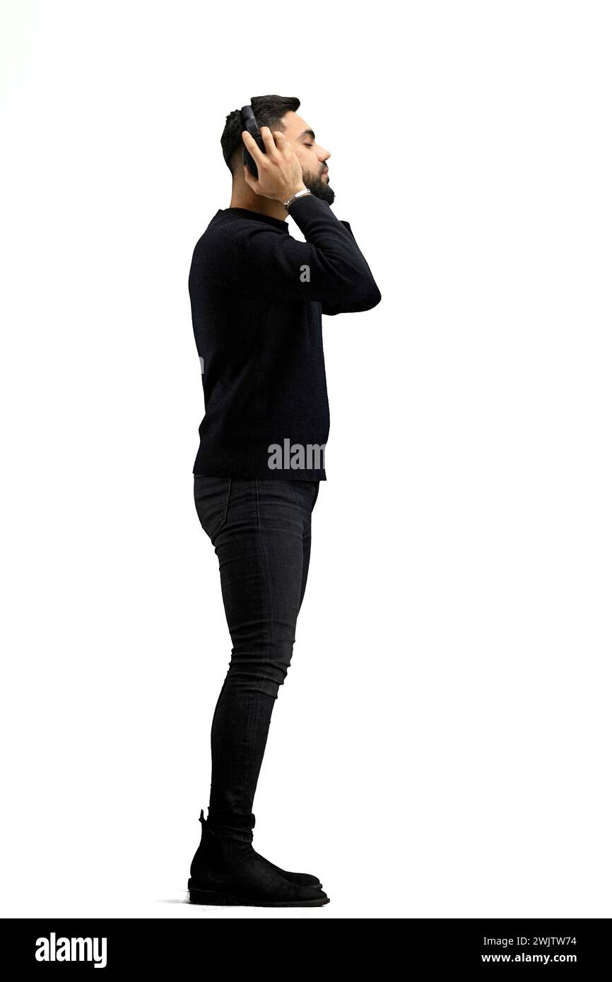 A man, in full height, on a white background, listens to music with ...