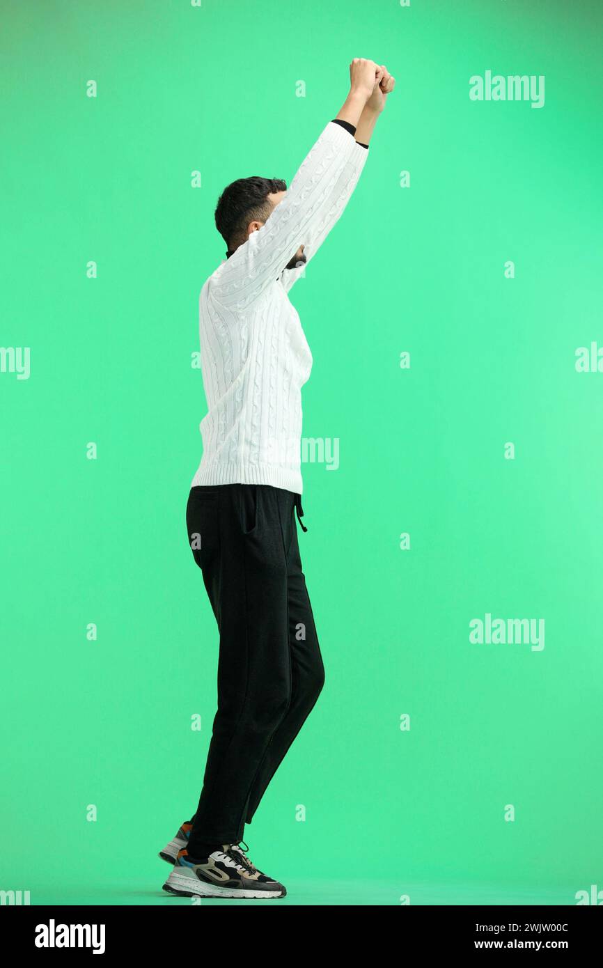 A man, full-length, on a green background, waving his arms Stock Photo ...
