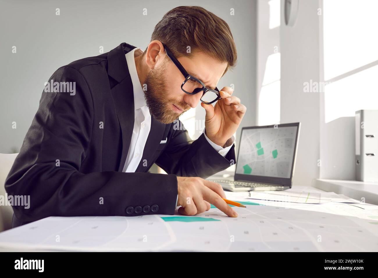 Professional cartographer working with printed cadastral map at table ...