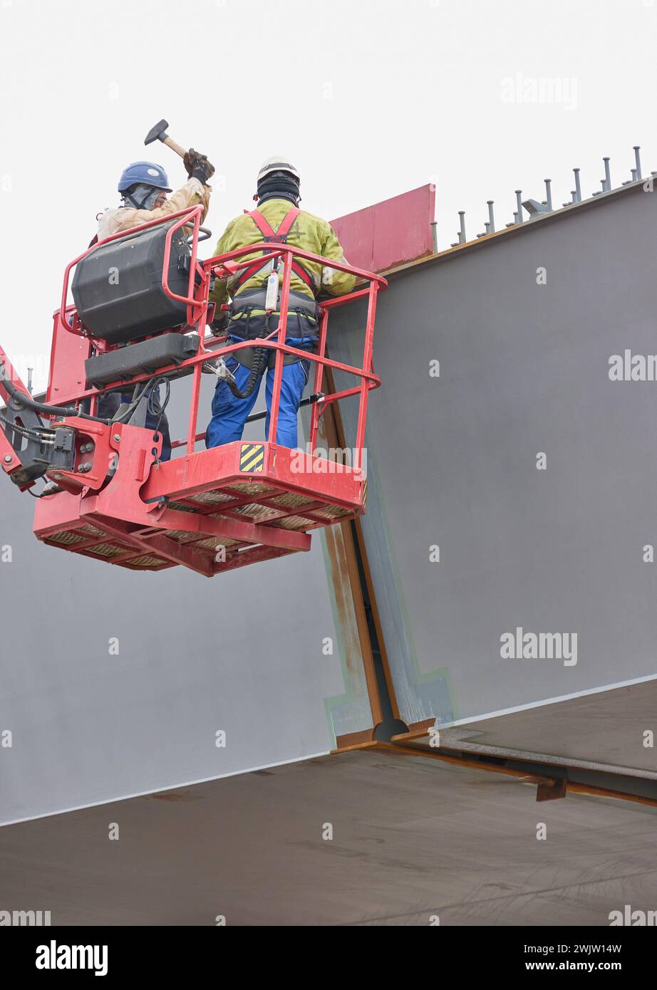 17 February 2024, Hamburg: Workers on a lifting platform set up a ...