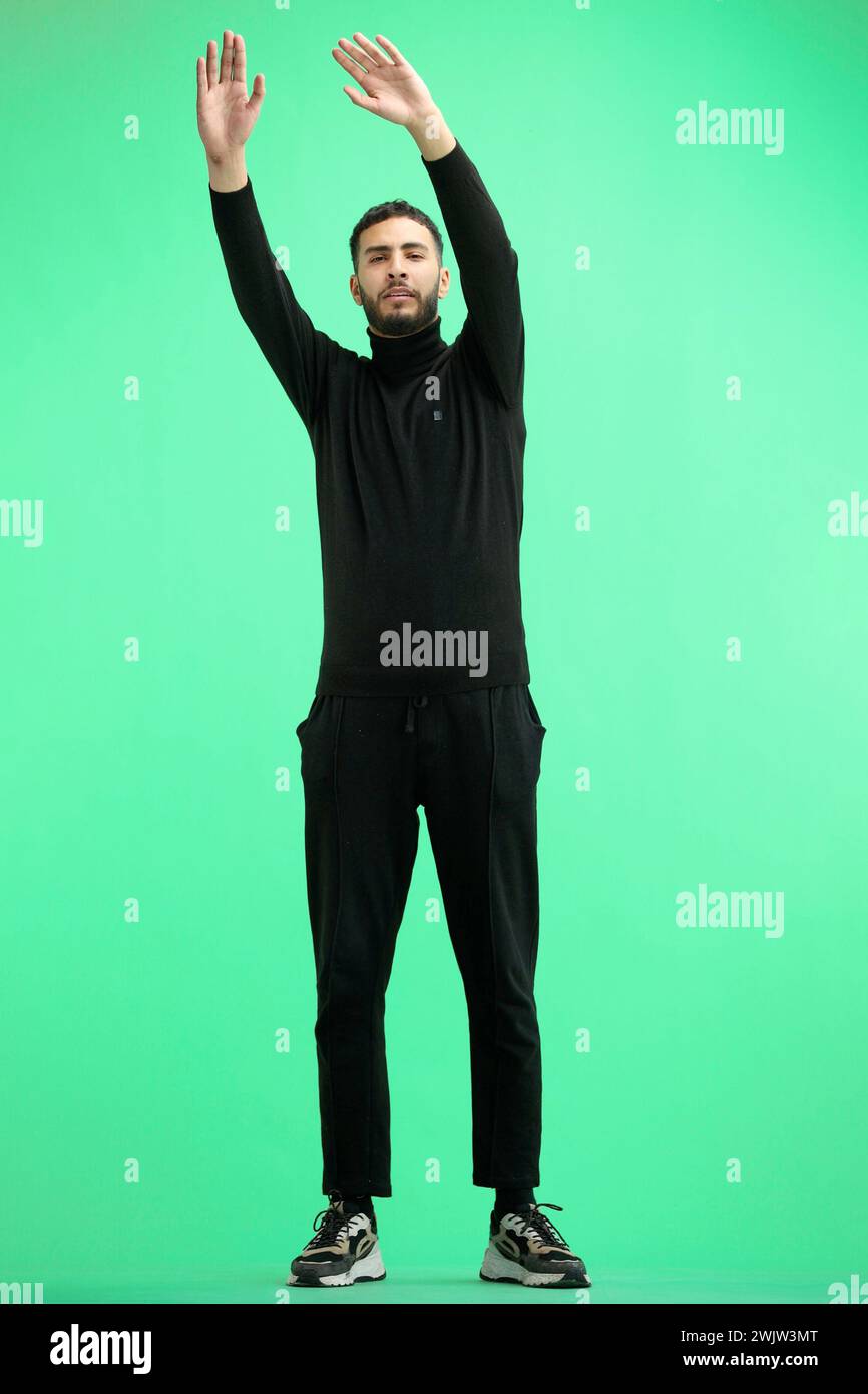A man, full-length, on a green background, waving his arms Stock Photo ...