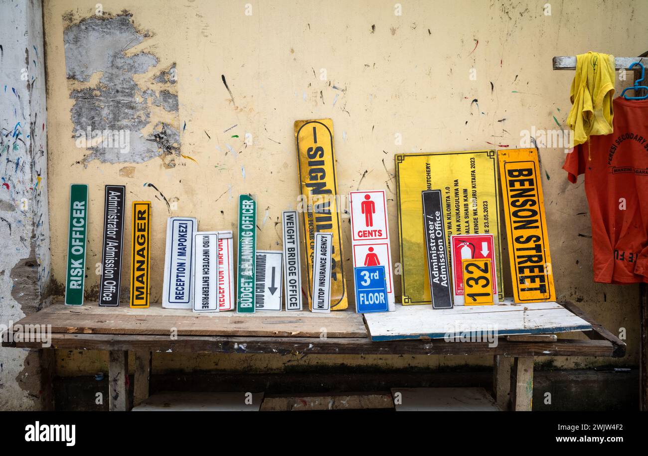 A signmaker shows examples of his signs for sale on a wooden table in ...
