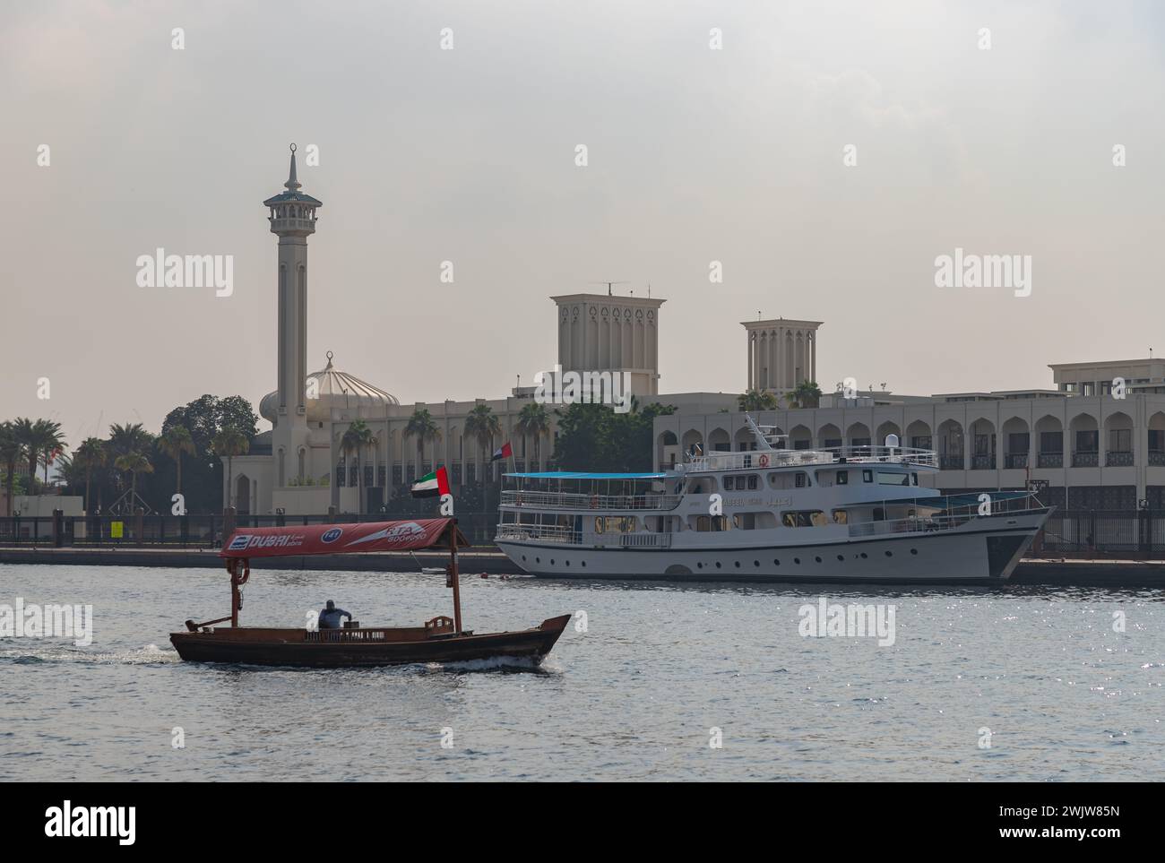 A picture of an abra boat at the Dubai Creek, in front of a larger ...