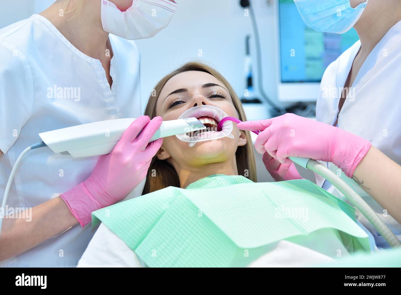 Woman dentist and assistant scaning patient's teeth with 3d scanner ...