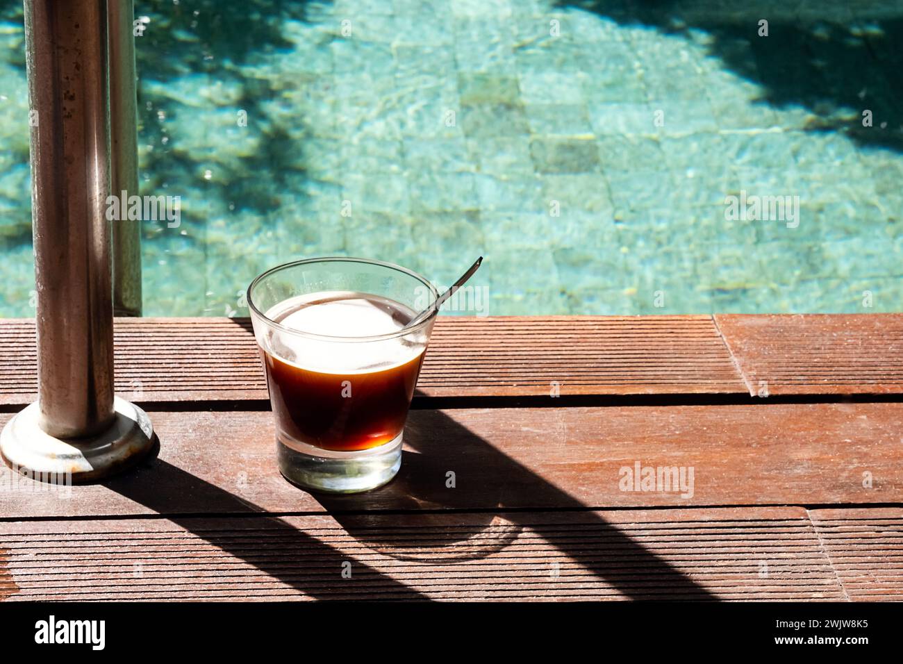 Morning coffee at poolside. Coffee glass standing near swimming pool ...