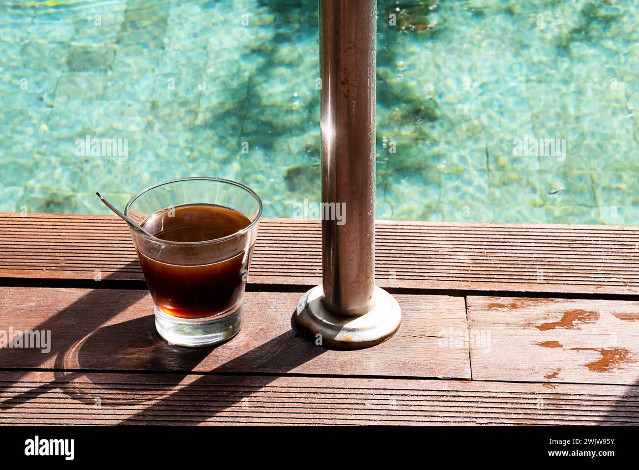 Morning coffee at poolside. Coffee glass standing near swimming pool ...