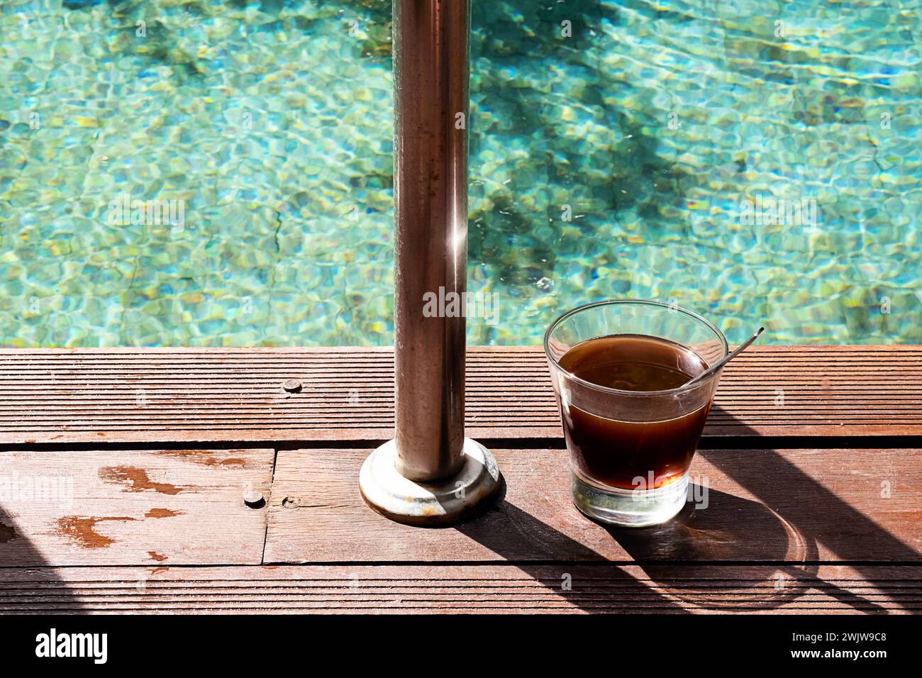 Morning coffee at poolside. Coffee glass standing near swimming pool ...
