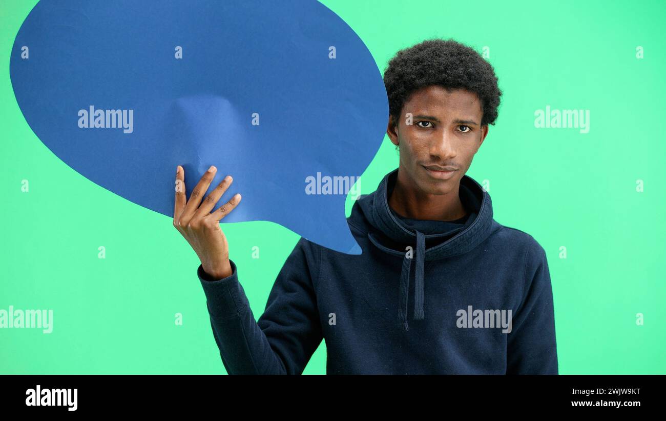 A man, close-up, on a green background, shows a blue comment sign Stock ...