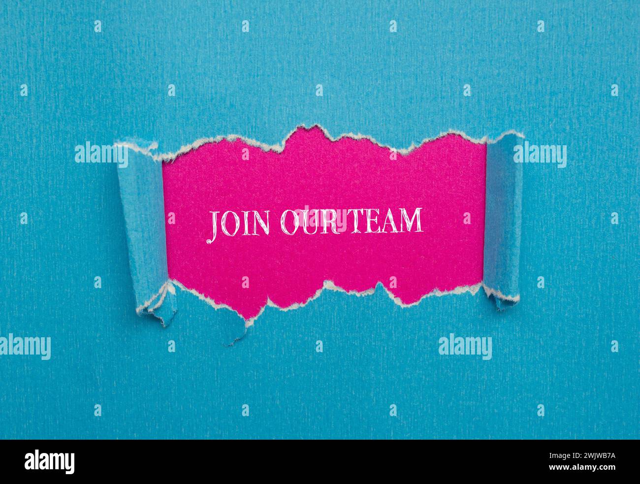 Join our team words written on blue torn paper piece with pink ...