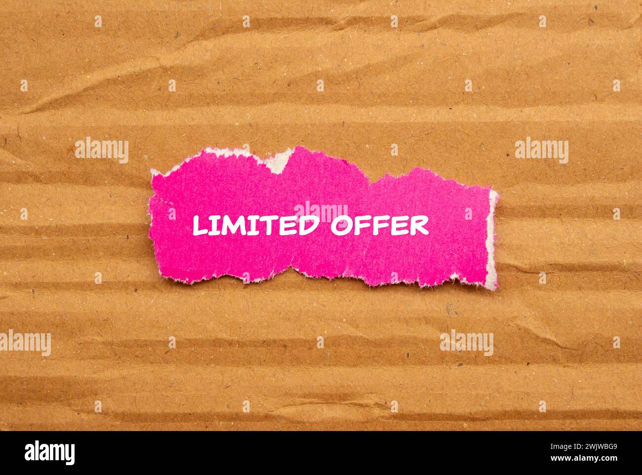 Limited offer words written on pink torn paper with cardboard ...