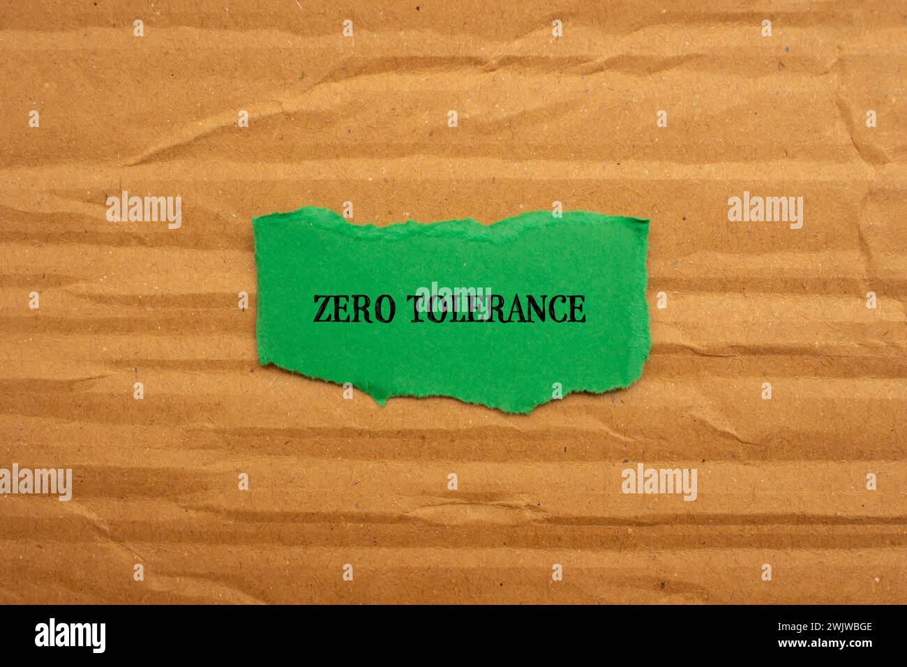 Zero tolerance words written on green torn paper piece with cardboard background. Conceptual ...