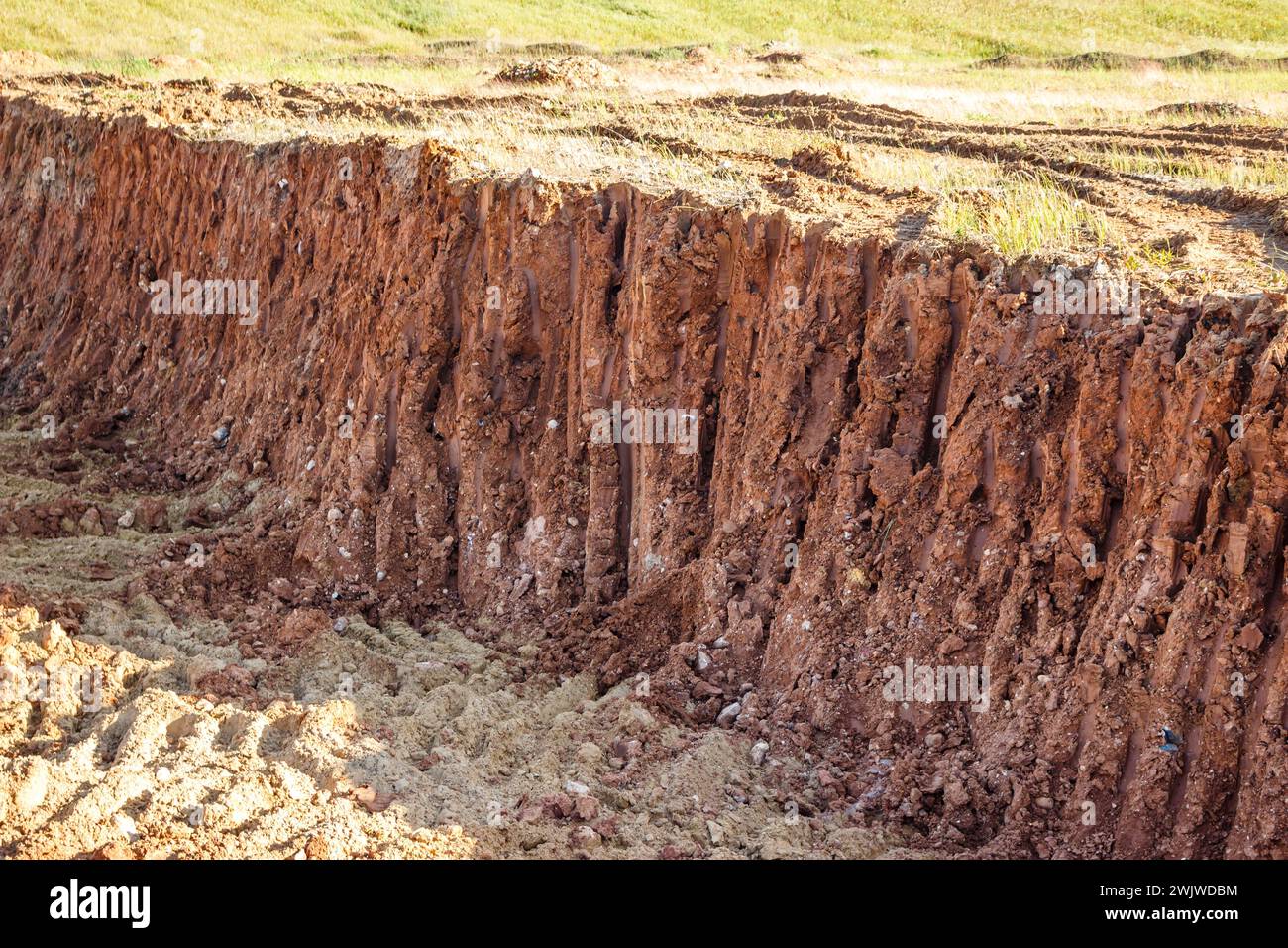 A layer of loamy soil dug down to sand by an excavator in a sand quarry ...