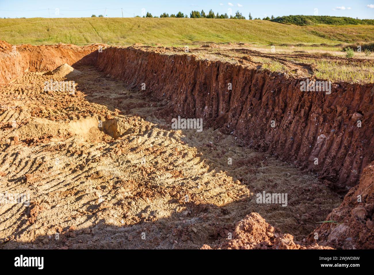 A layer of loamy soil dug down to sand by an excavator in a sand quarry ...