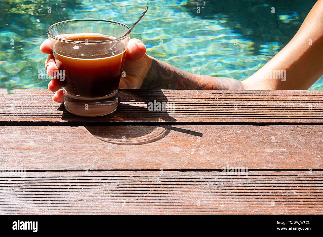 Woman drinking coffee in the swimming pool. Morning coffee at poolside ...