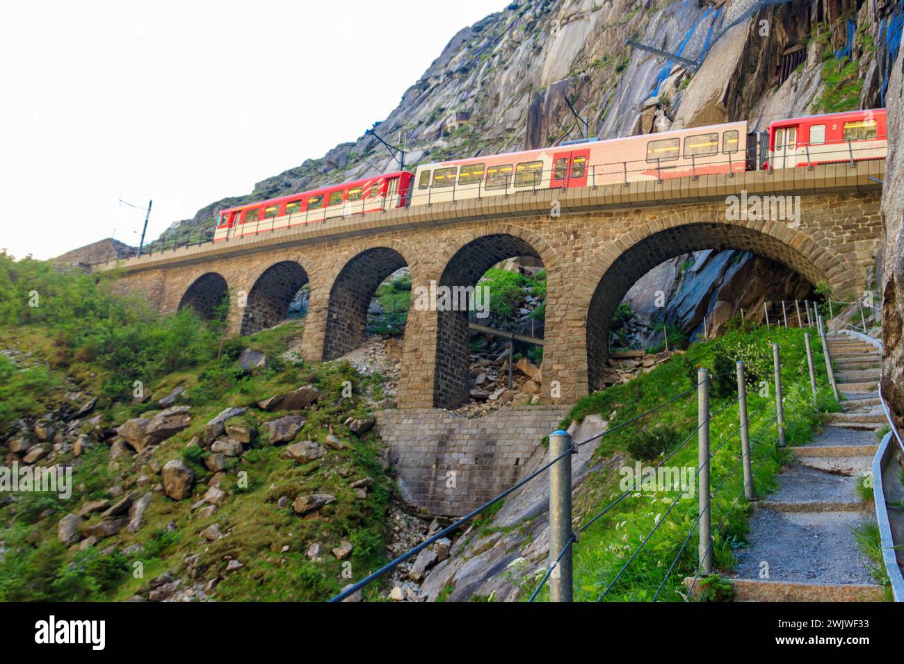 Red train passing by Devil's bridge at St. Gotthard pass on the Swiss ...