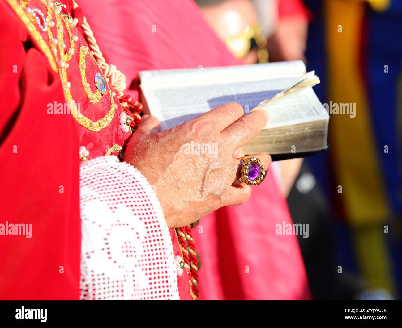 elderly bishop with red cassock and the ancient bible with the sacred ...