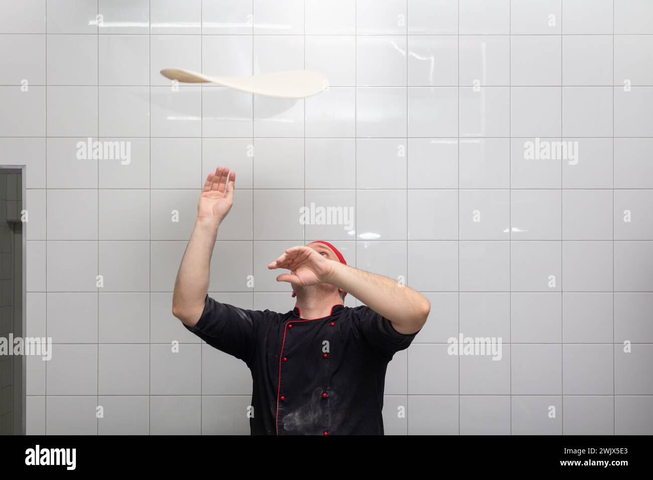 Pizzaiolo stretches the dough by tossing it into the air and rotating ...